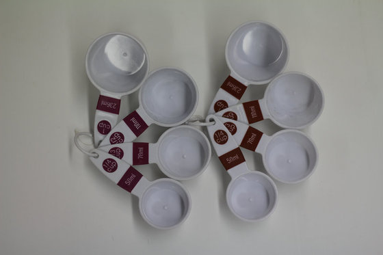 Measuring cup bianca messa, prodotti della cucina con la maniglia di tocco morbido