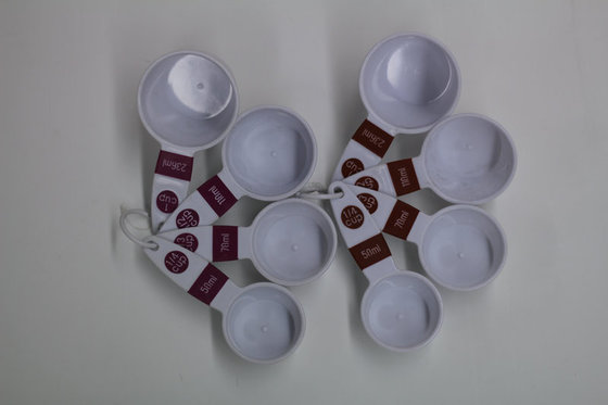 Measuring cup bianca messa, prodotti della cucina con la maniglia di tocco morbido